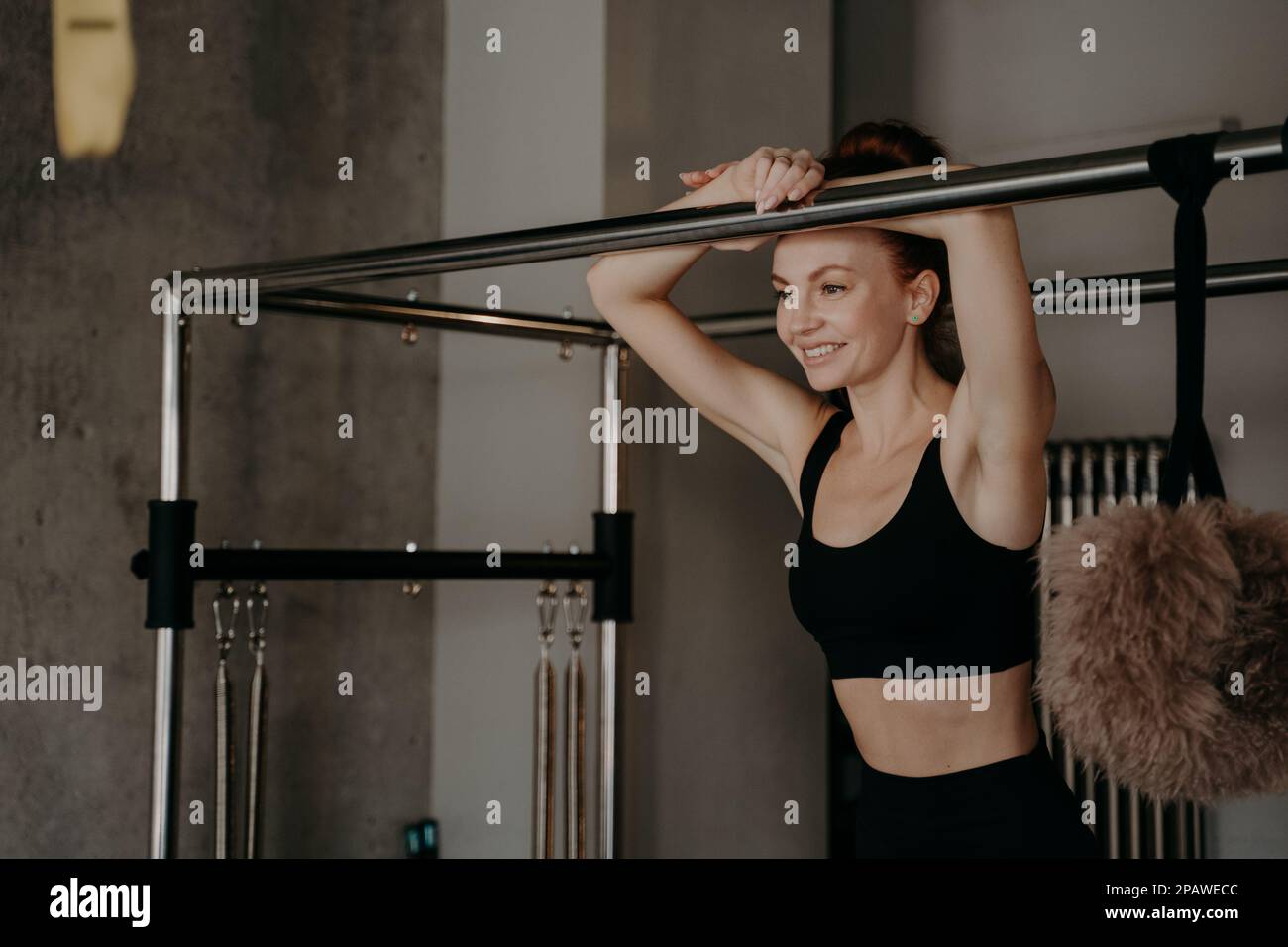 Smiling fit young ginger woman ballerina in sports clothes leaning on ...