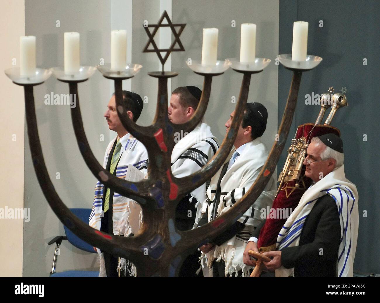 Members of the Jewish community hold a Torah in the synagogue in ...