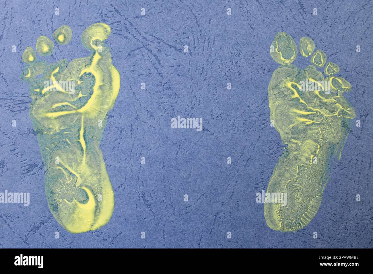 Baby feet prints made with yellow paint on blue textured paper ...