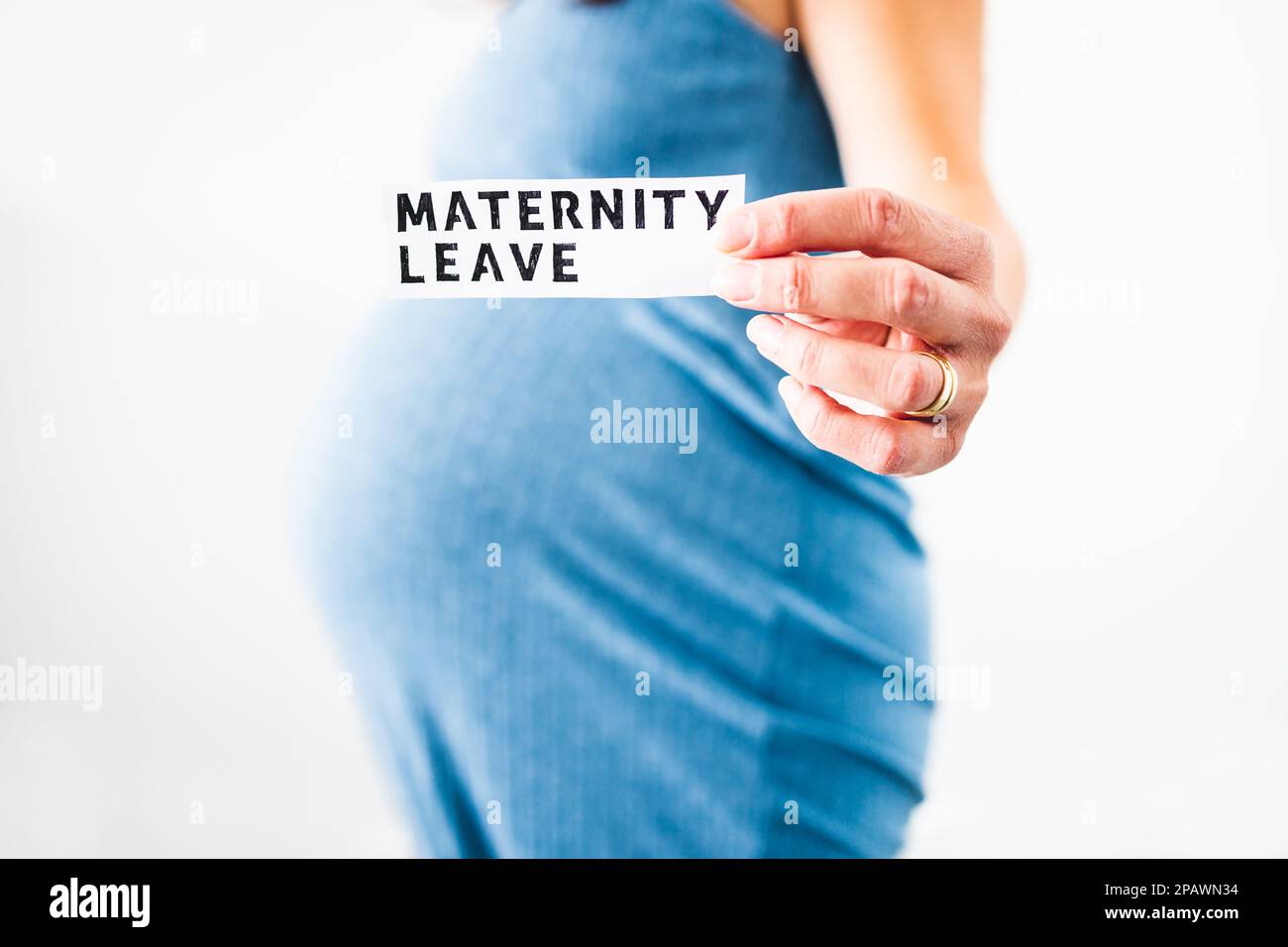 pregnant woman holding Maternity Leave sign towards the camera wearing ...