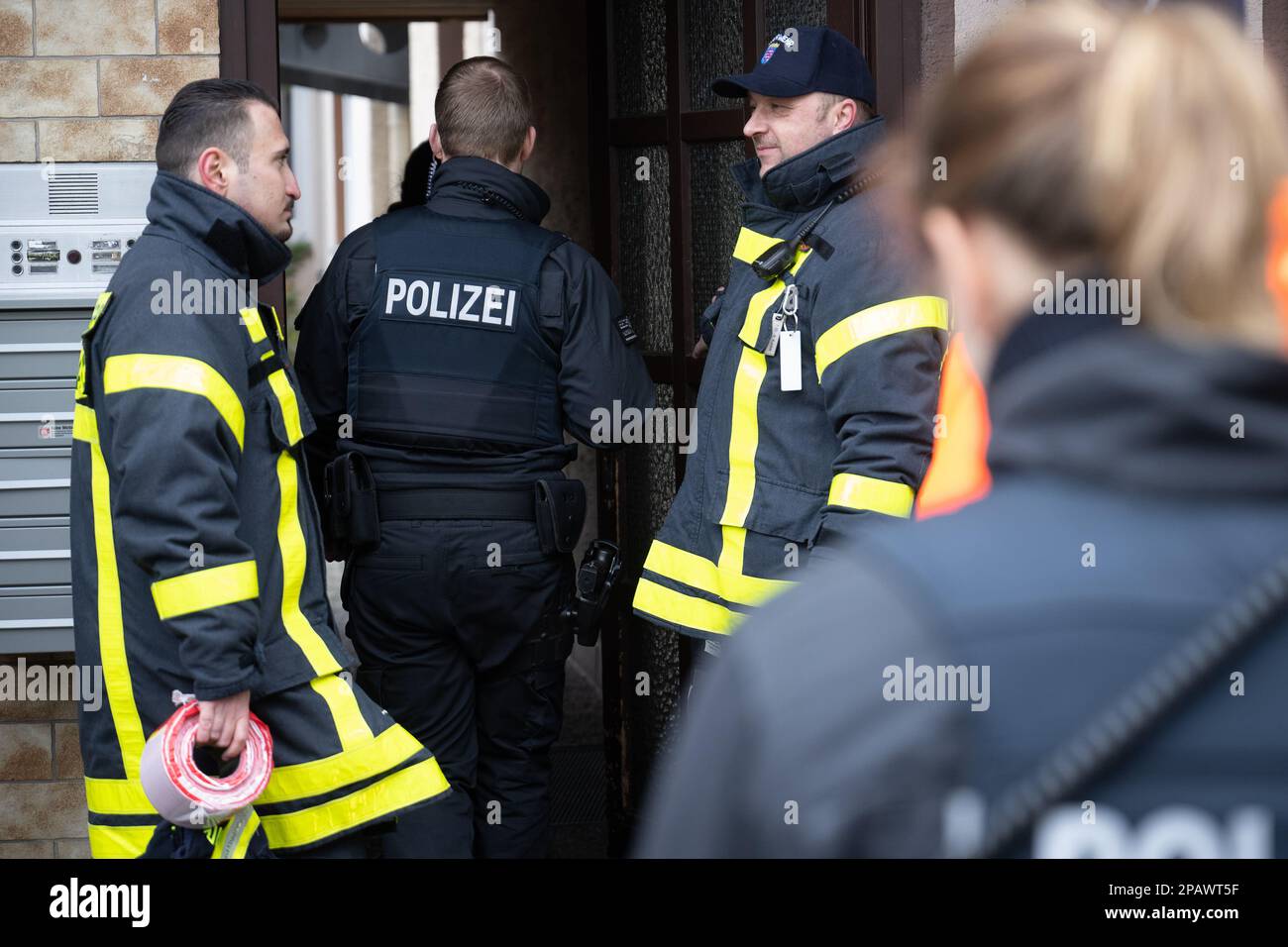 Hanau, Germany. 12th Mar, 2023. Employees of the fire department and police go from house to ...