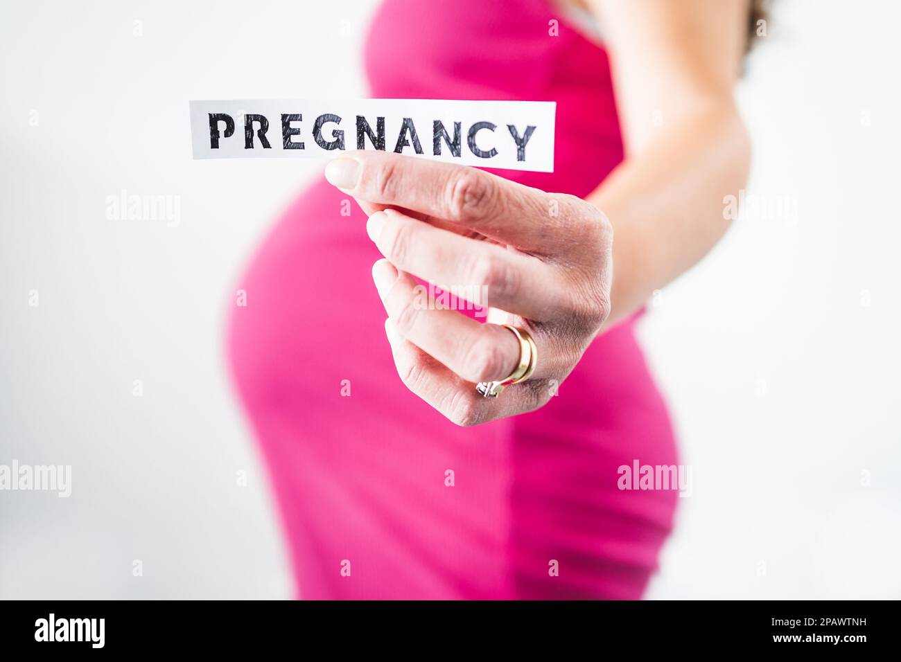 pregnant woman holding Pregnancy sign towards the camera wearing pink ...