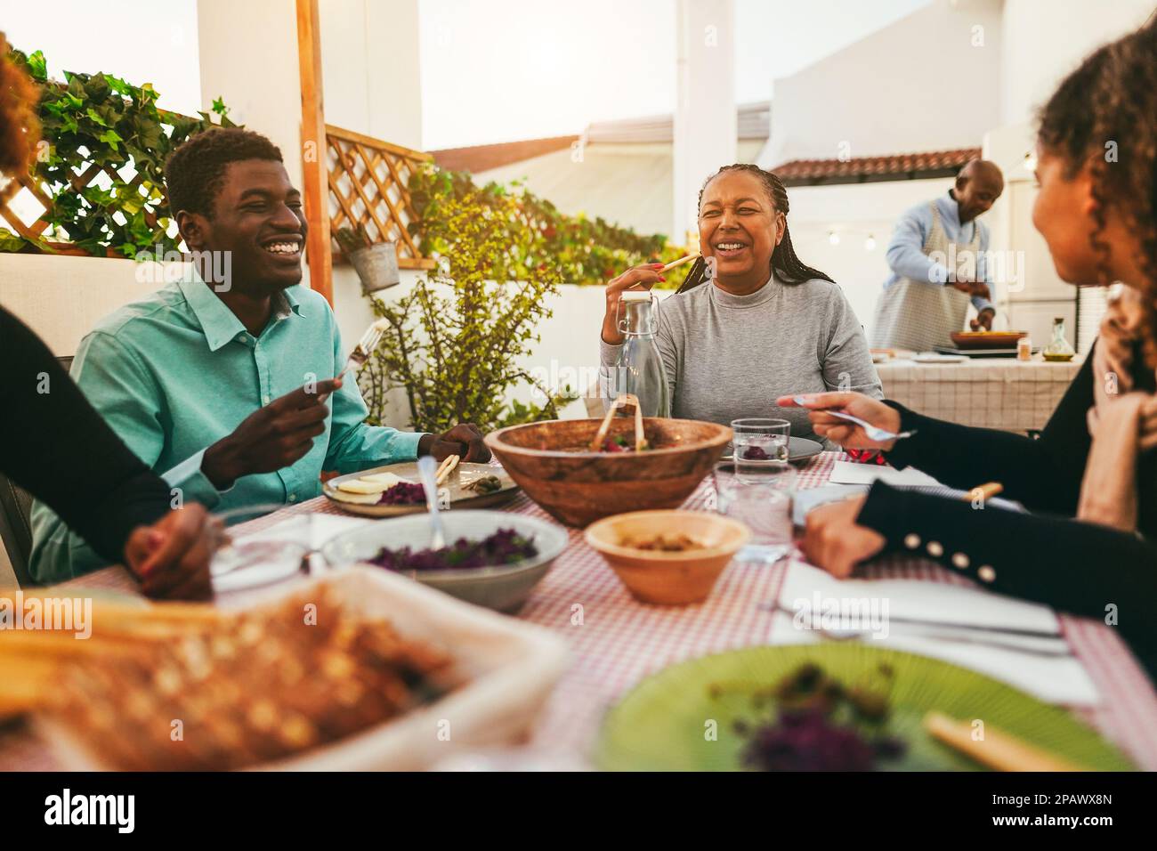 Happy african family eating lunch together at home terrace outdoor ...