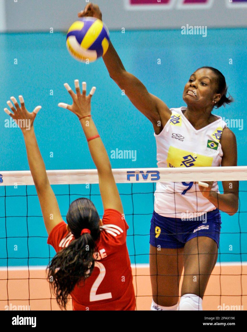 Fabiana Claudino of Brazil spikes the ball against Mirtha Uribe of Peru ...