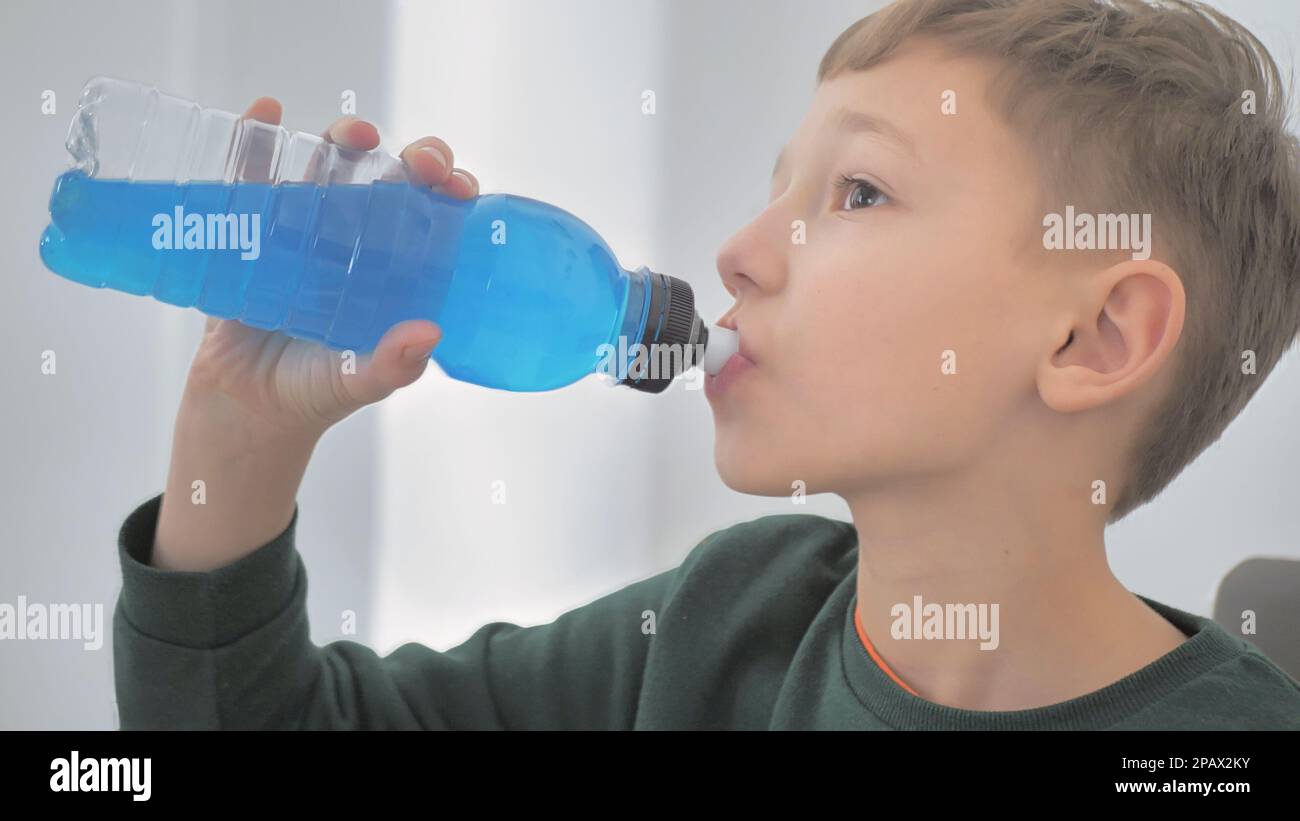 Taking a break. Side view of sporty teenager drinking blue energy drink ...
