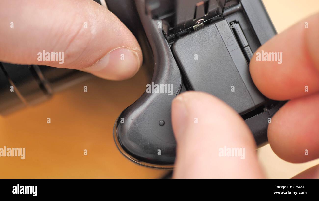 A photographer changes the battery in his digital SLR camera while ...