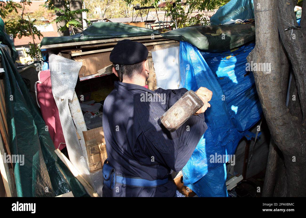 An Italian police officer hammers makeshift houses on the Tiber river ...