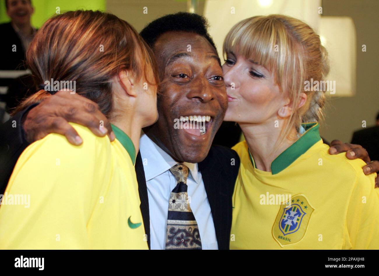 Former Brazil soccer star Pele, center, is kissed by two models during ...