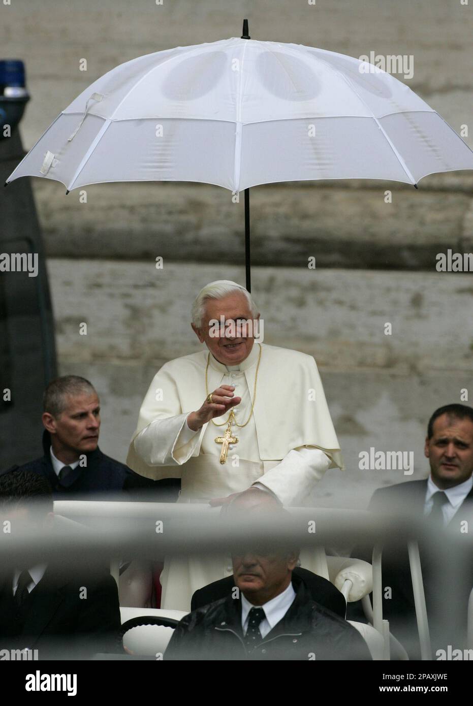 Pope Benedict XVI under a white umbrella, arrives for a rainy general ...