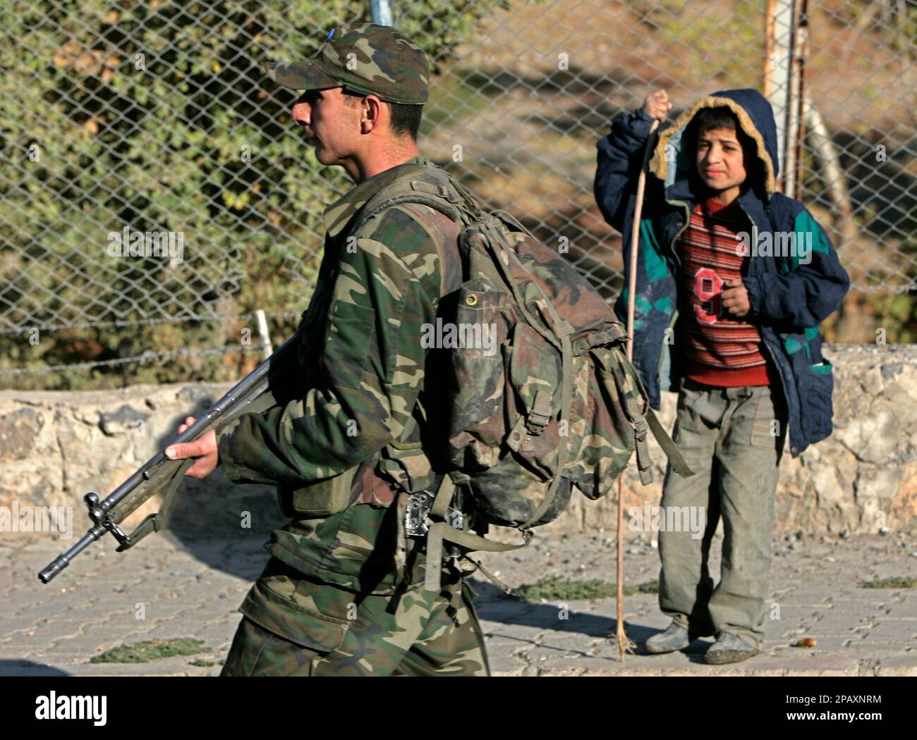 A boy looks at a Turkish soldier on patrol near the Iraq border, in the ...