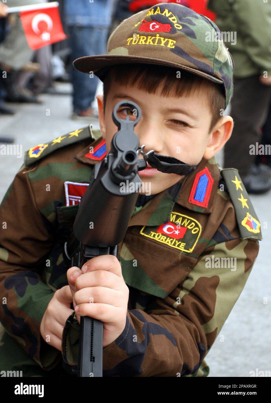 A Turkish boy, wearing a commando-like uniform, poses with his toy gun ...