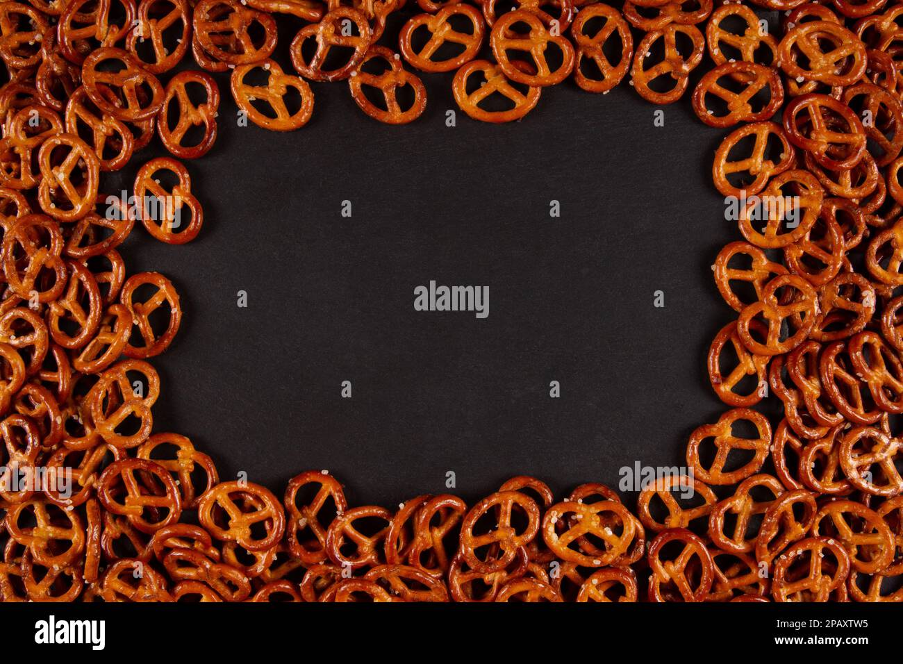 Rectangular frame of mini pretzels on black background. Dark backdrop ...