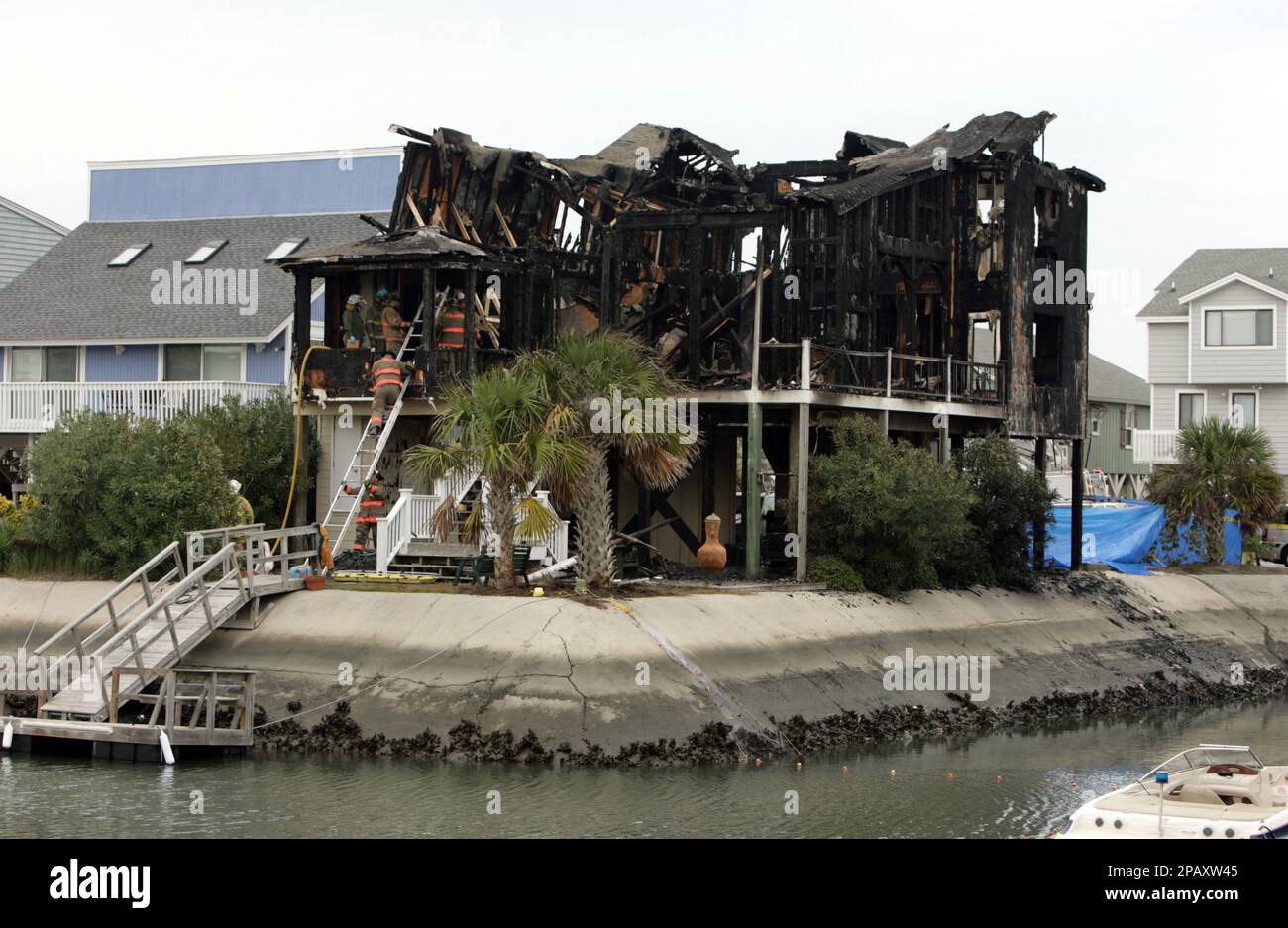 Firefighters work at the scene of a beach house that burned and ...