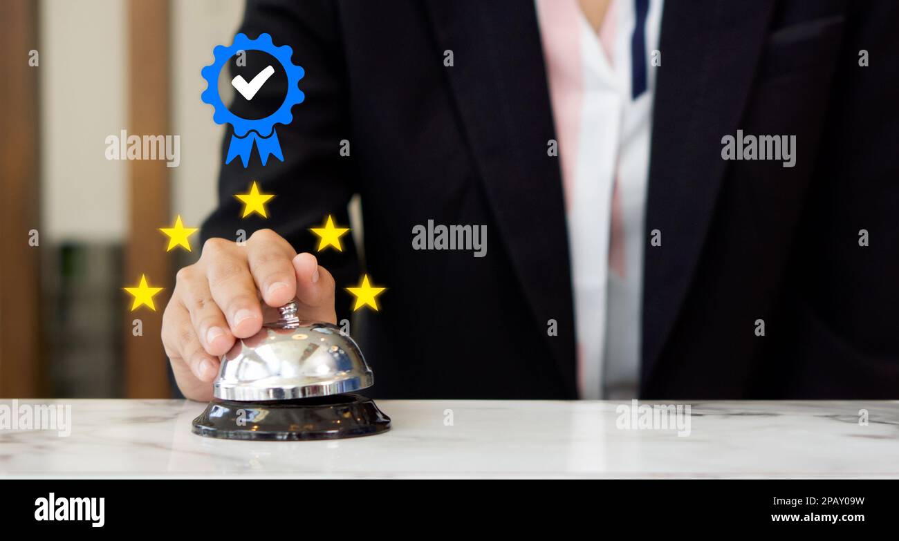 Businesswoman hand ringing silver service bell on hotel reception desk ...