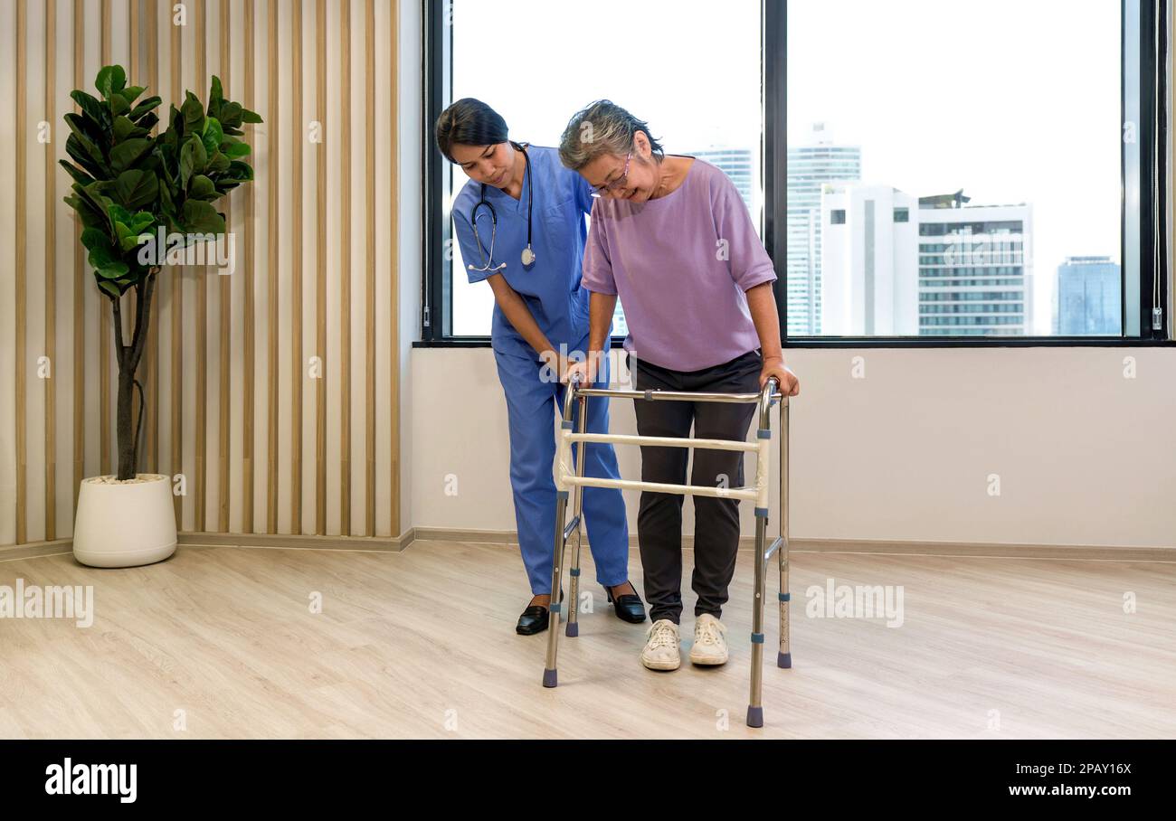 Woman Physical Therapist In Blue Uniform Help An Elderly To Exercise Woman Physical Therapist In Blue Uniform Help An Elderly To Exercise