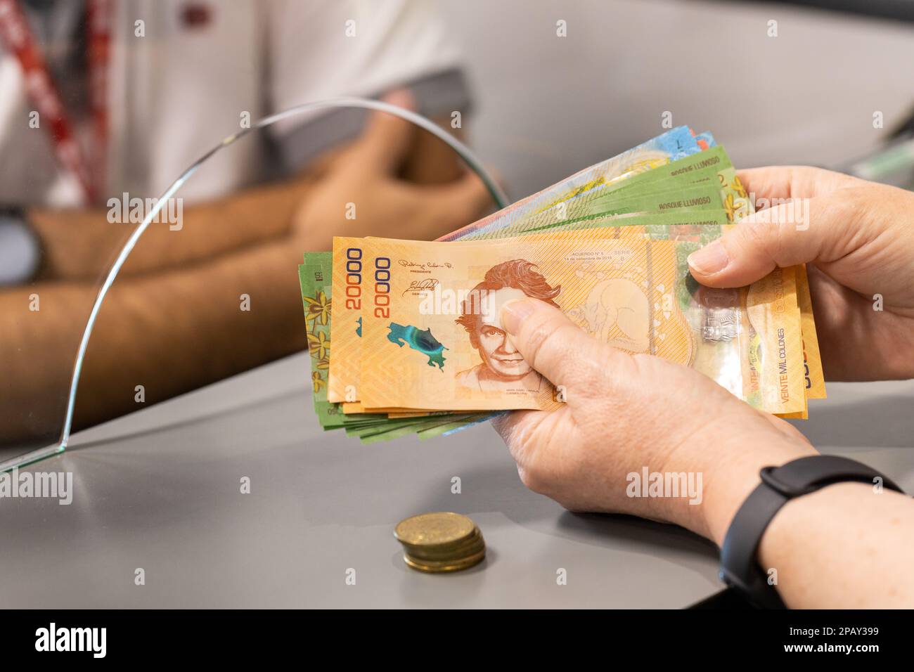 Costa Rica money, A woman stands at the cash register with a lot of ...