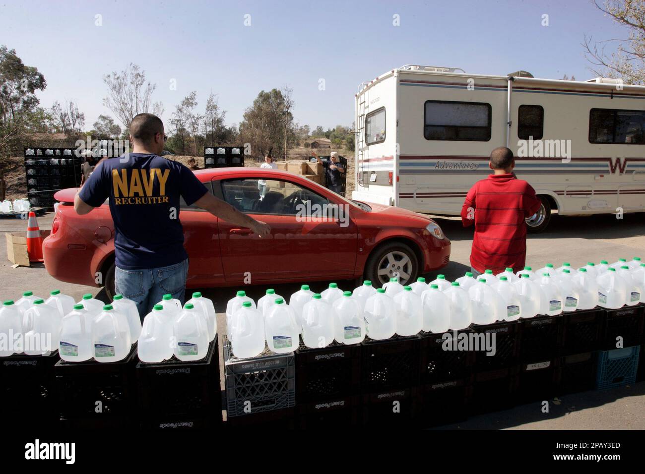 Cars pull up to receive bottled water from volunteers as people return ...