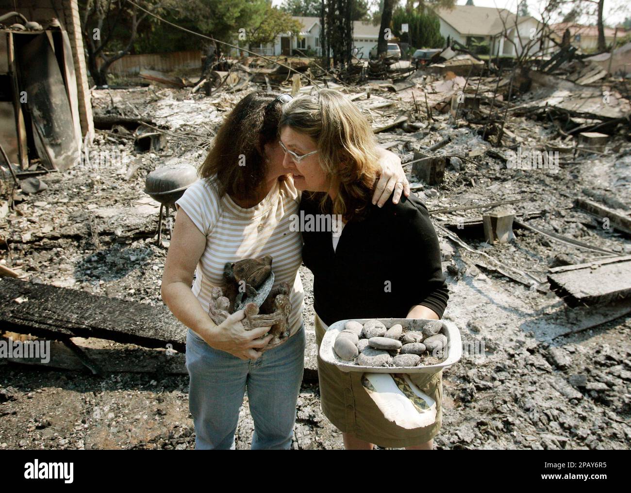 Mary Tabar, right, gets a hug from neighbor Cindy Keane as the two sift ...