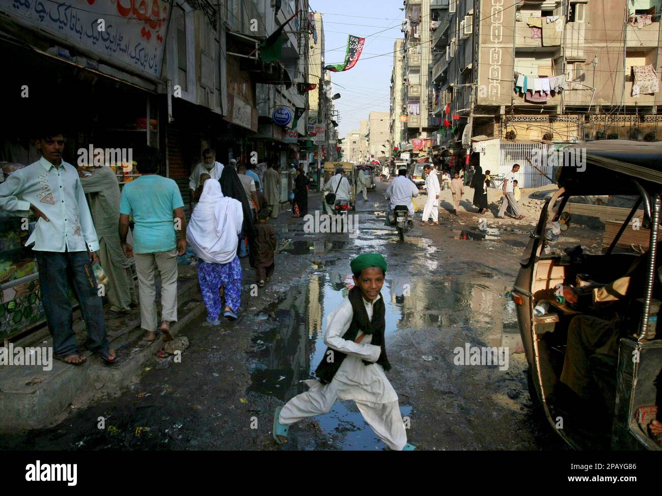 A boy leaps over a puddle in a street of a Karachi slum on Monday, Oct ...