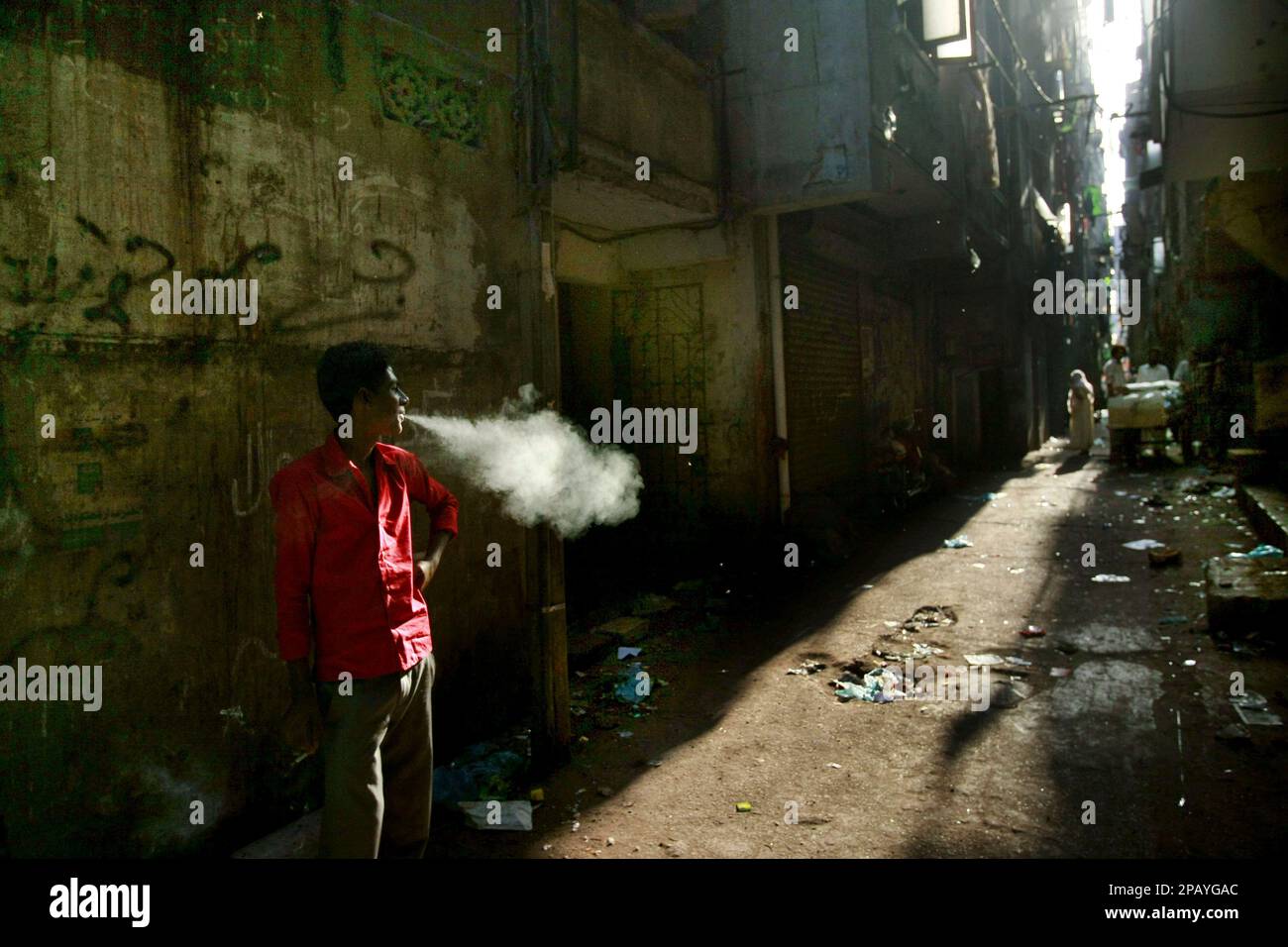 A Pakistani man smokes hashish in a narrow street in a Karachi slum on ...