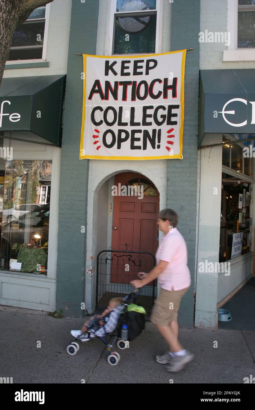 A pedestrian pushes a baby stroller past a sign that reads "Keep ...