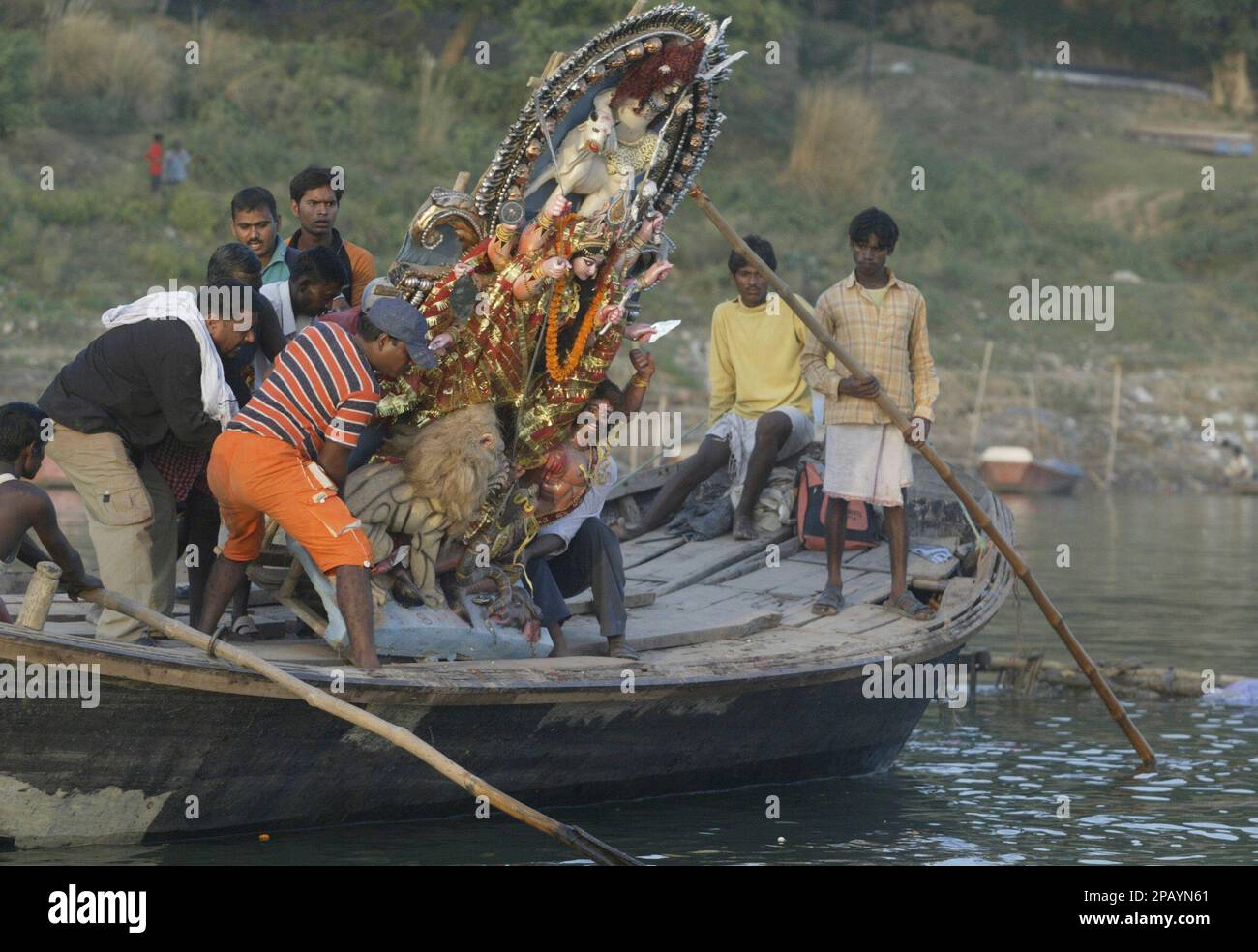 Indian Hindu devotees use a boat to immerse an idol of Goddess Durga ...