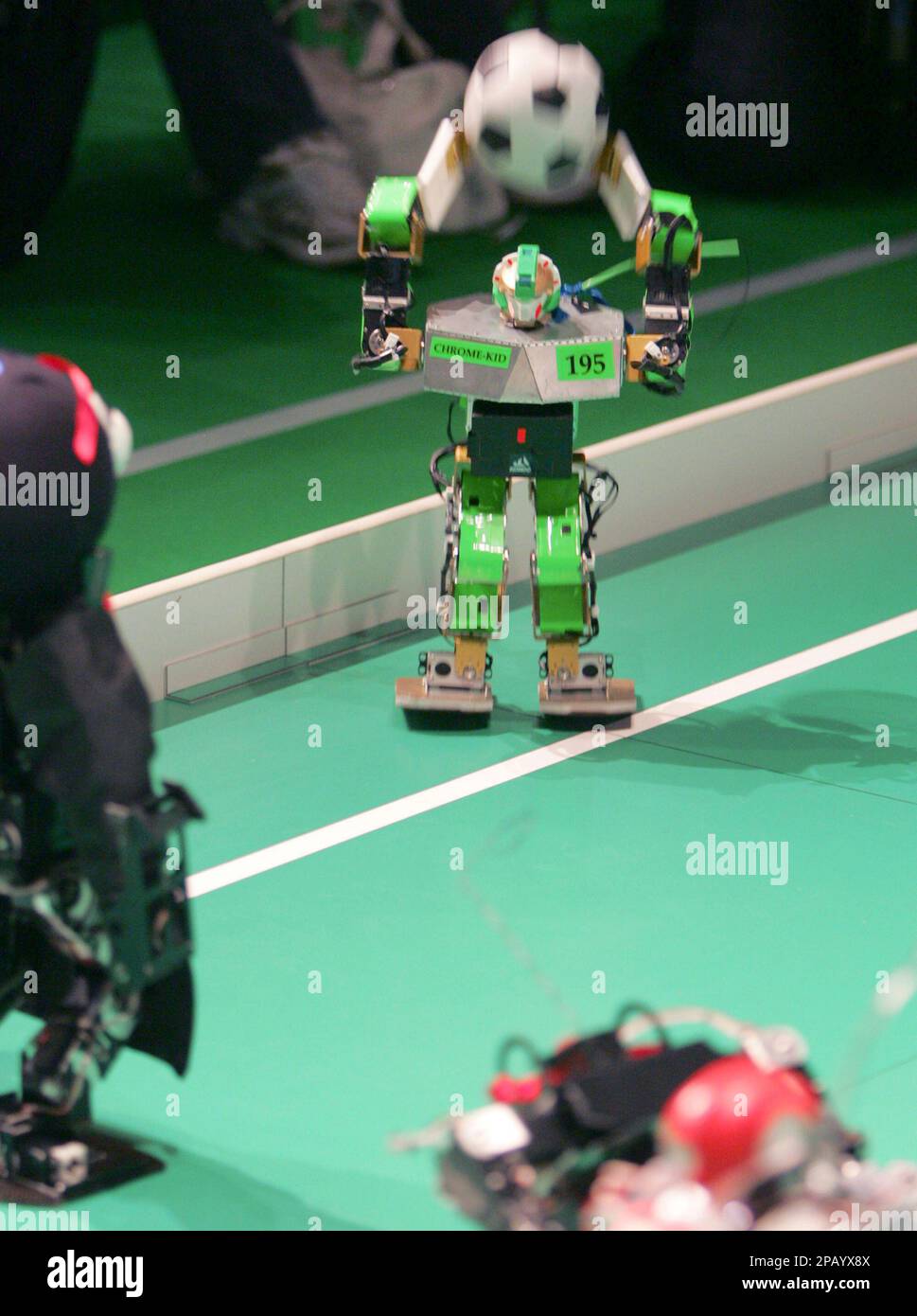 A robot throws a ball into the field during a soccer match by remote ...