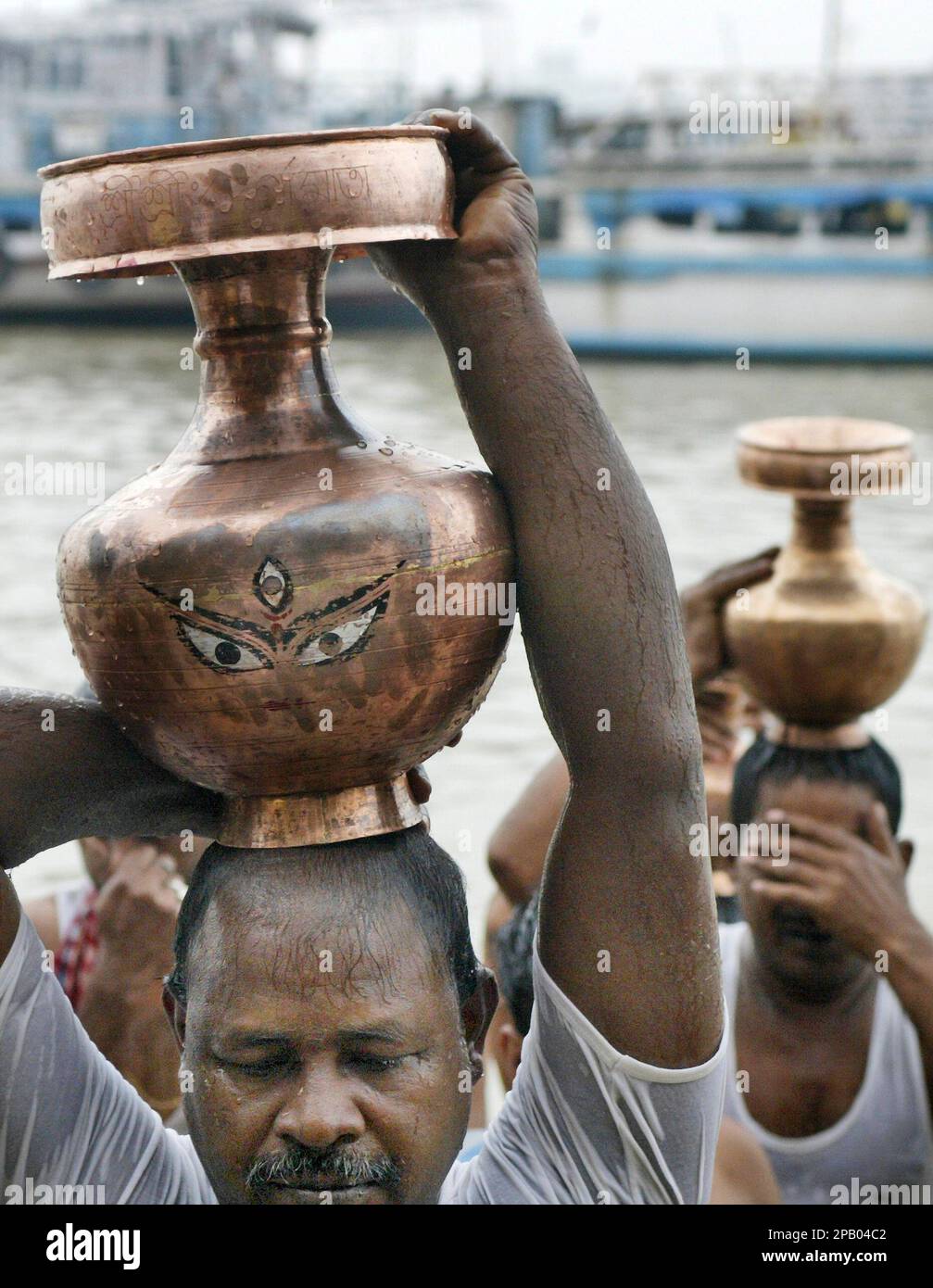 Hindu devotees carry holy water from the river Ganges for praying, at ...