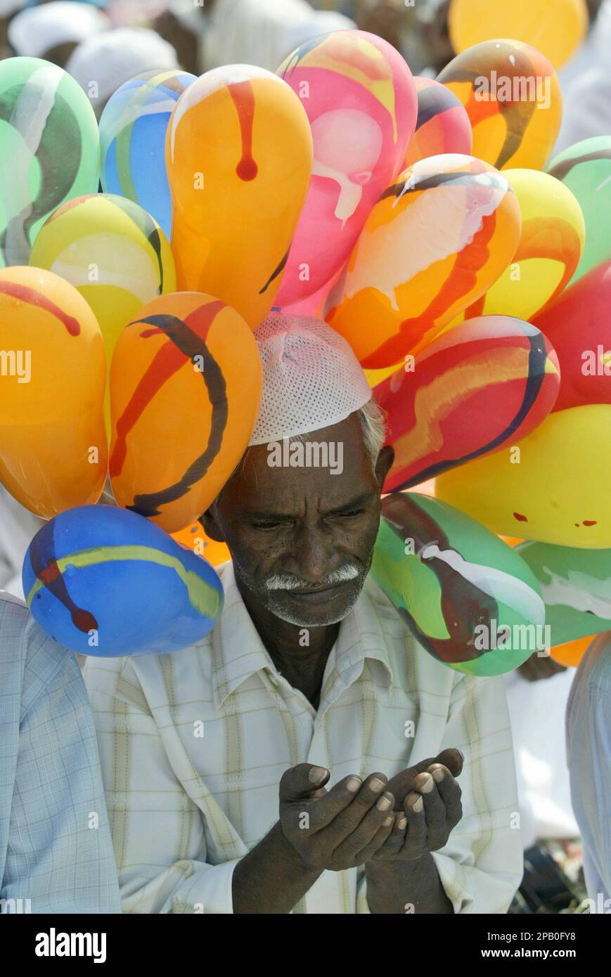 A Muslim offers prayers on the occasion of Eid al-Fitr, as balloons set ...