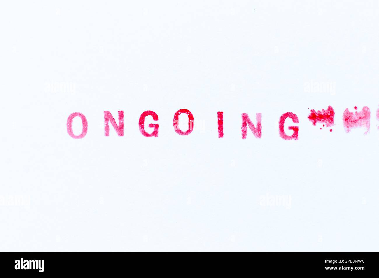 Red color ink rubber stamp in word ongoing on white paper background ...