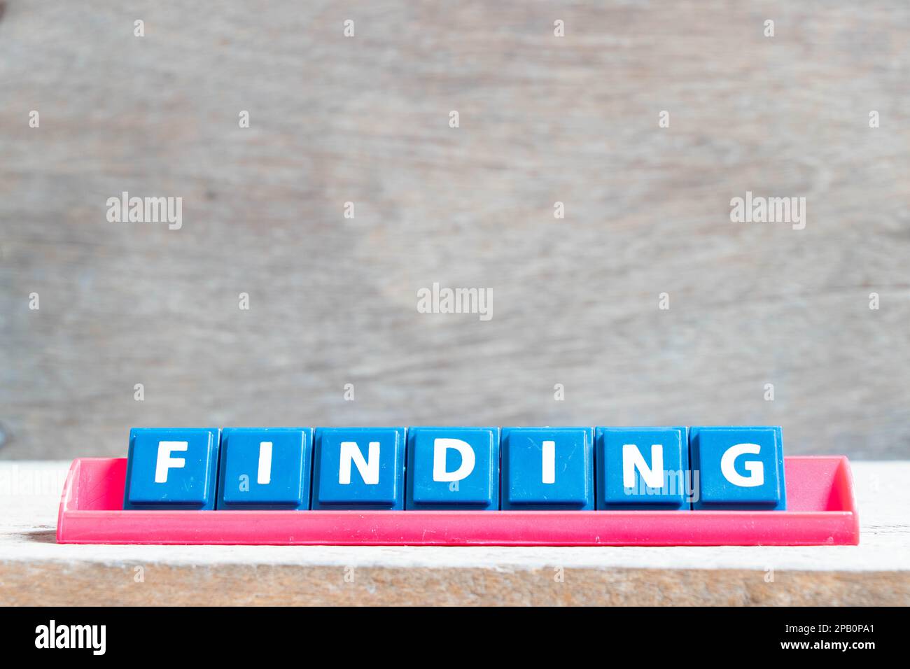 Tile alphabet letter with word finding in red color rack on wood ...
