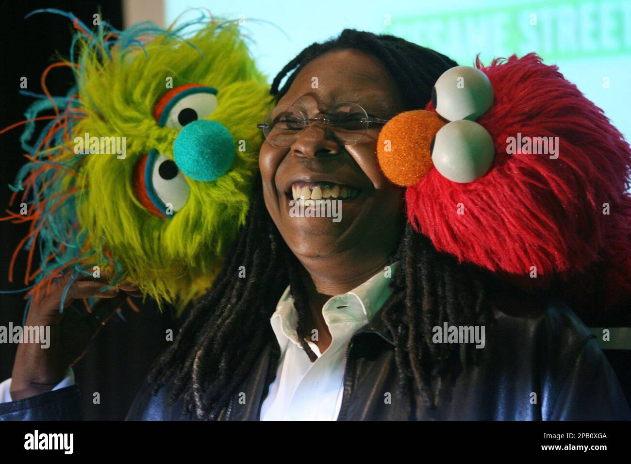Elmo, right, and Azibo, a new Muppet character, left, kiss Whoopi ...