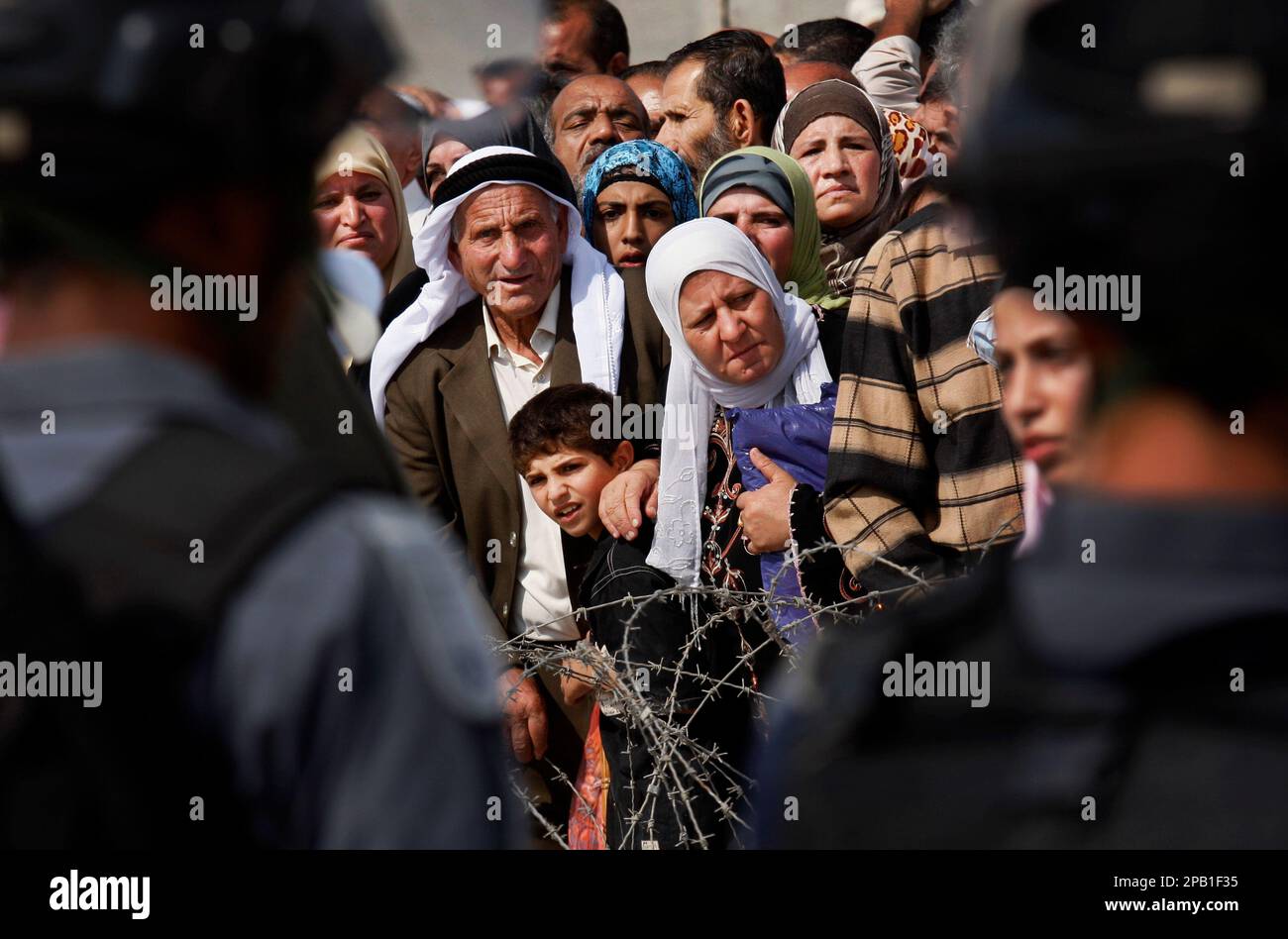 Palestinian Muslim worshippers wait behind a razor-wire barricade as ...