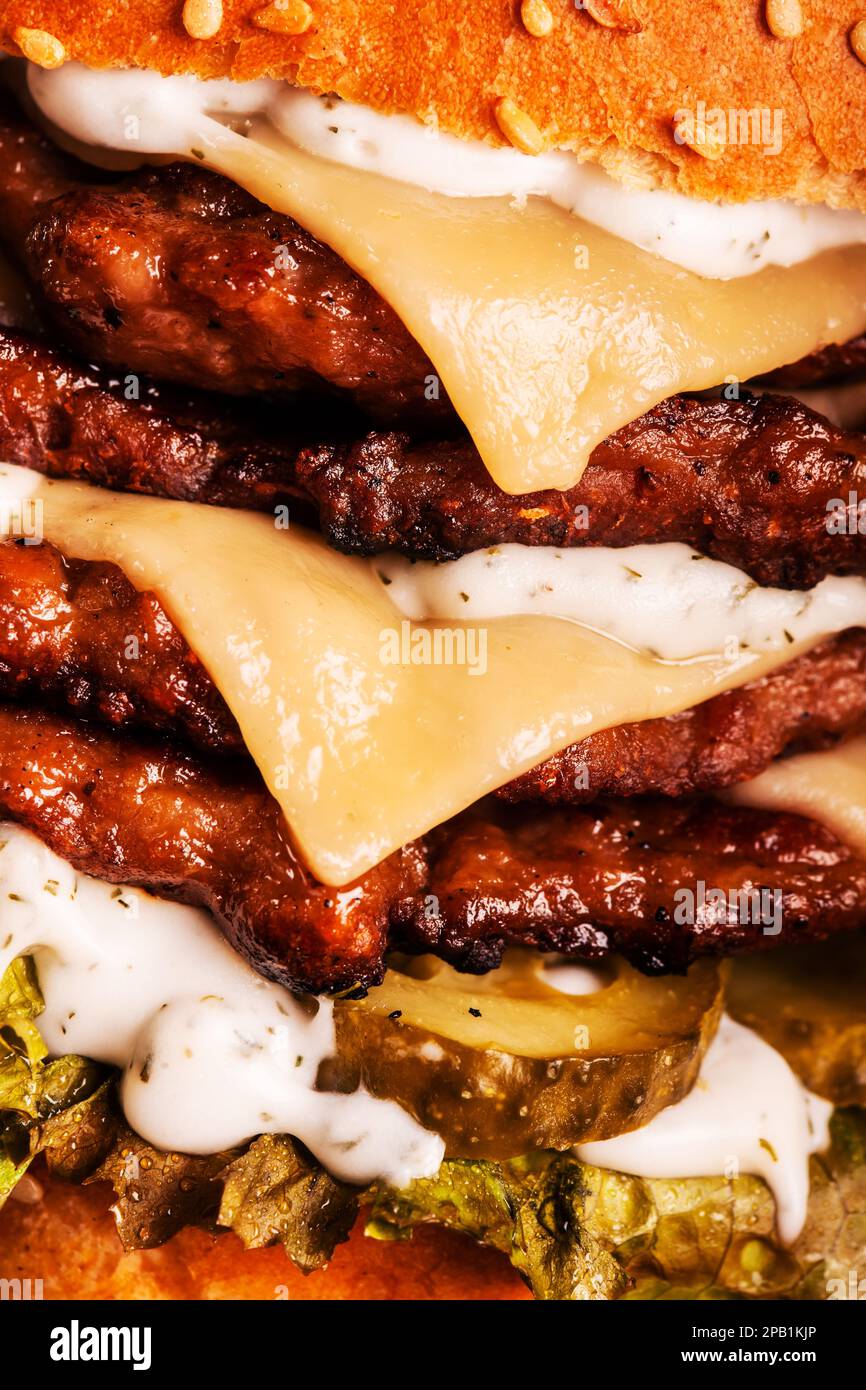 Abstract junk food. Quadruple burger with cheese cucumber and lettuce ...