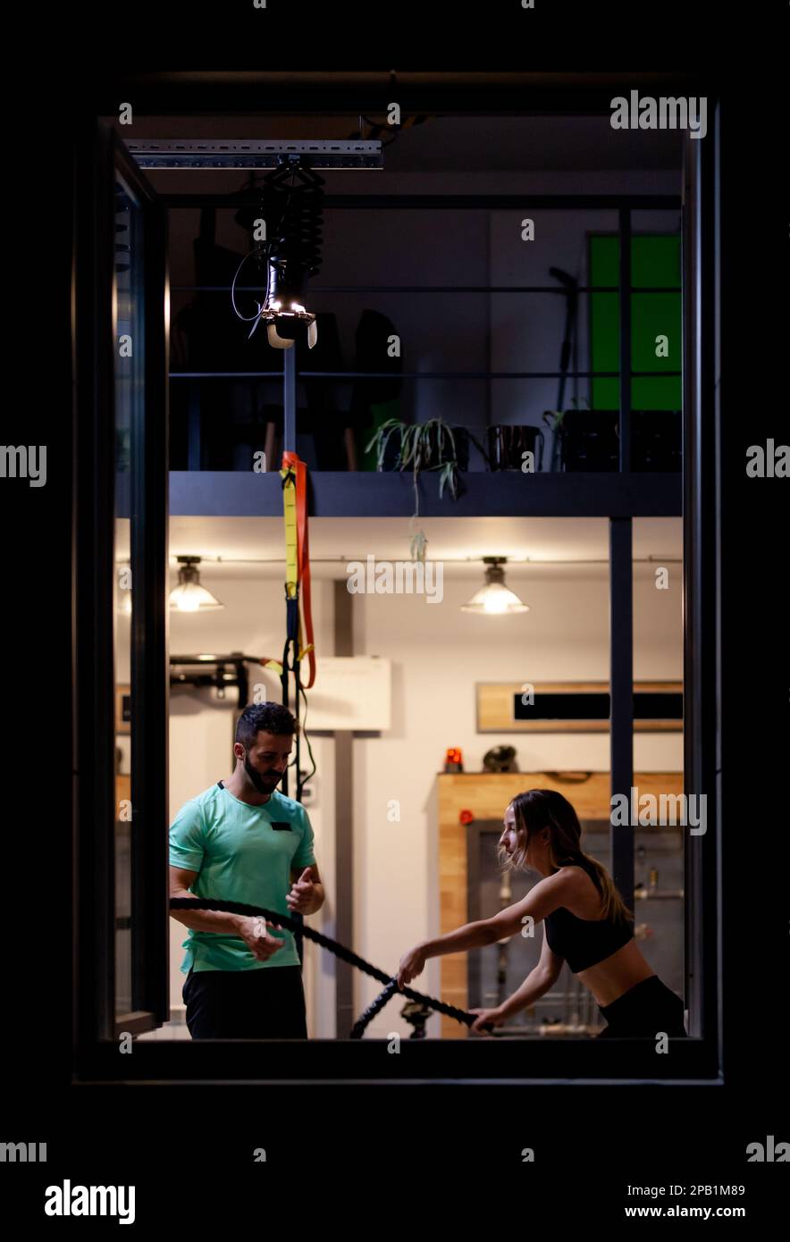 Fit girl with exercising with ropes with a male fitness instructor in a ...