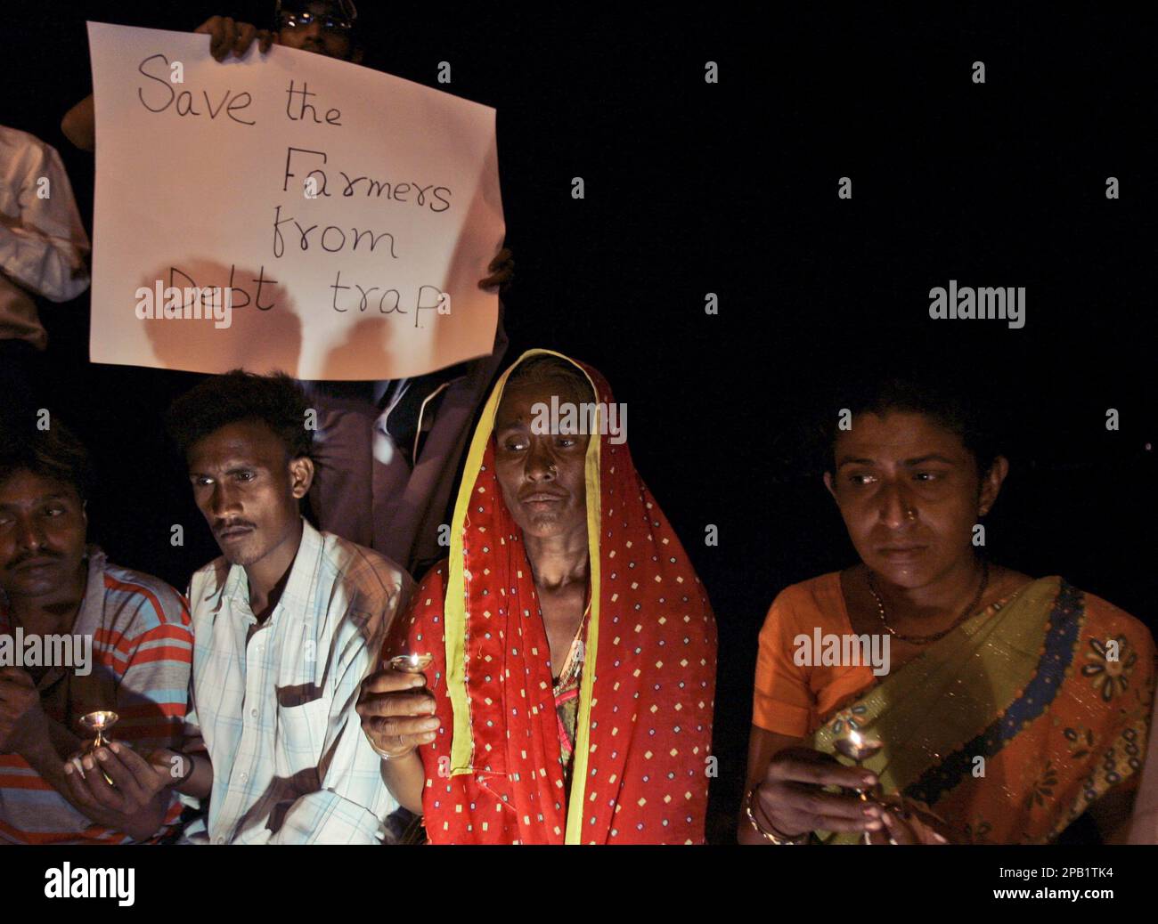 Family members of farmers who committed suicide, take part in a candle ...