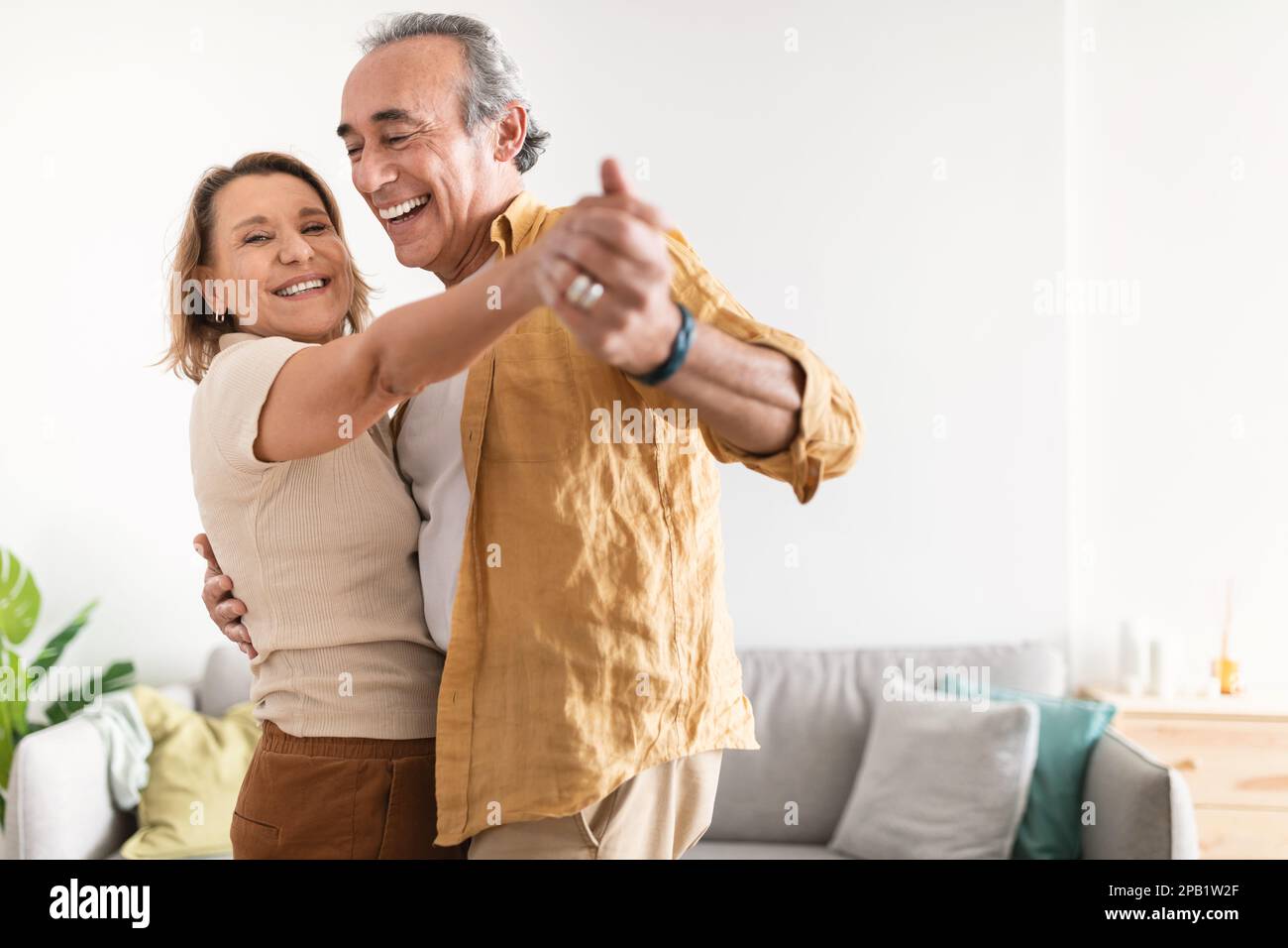 Cheerful retired spouses husband and wife dancing and laughing in ...