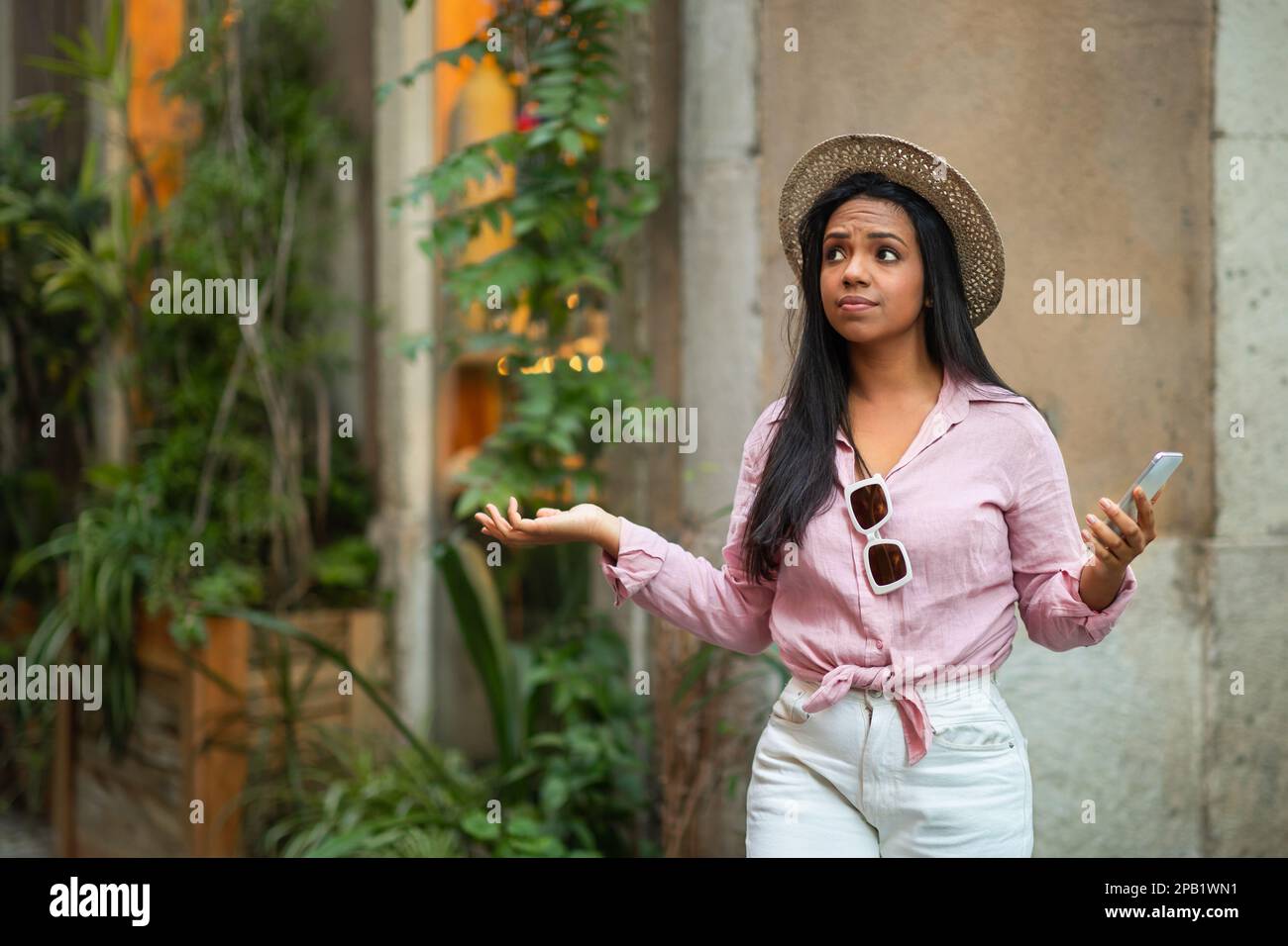 Confused despaired young african american woman in hat with smartphone ...