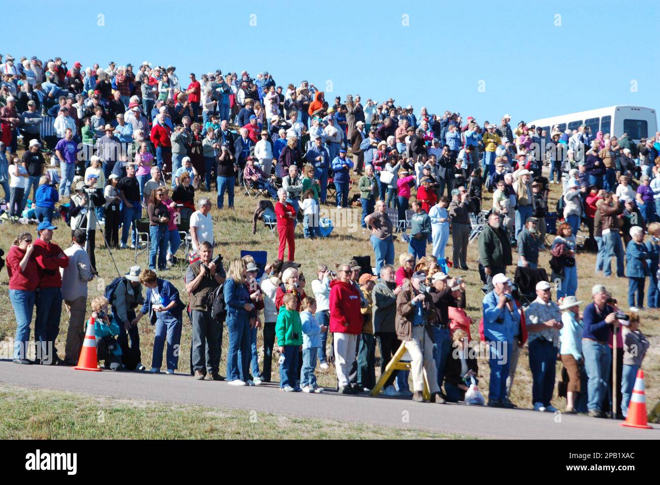 A crowd watch horseback riders guide buffalo into corrals during Custer ...