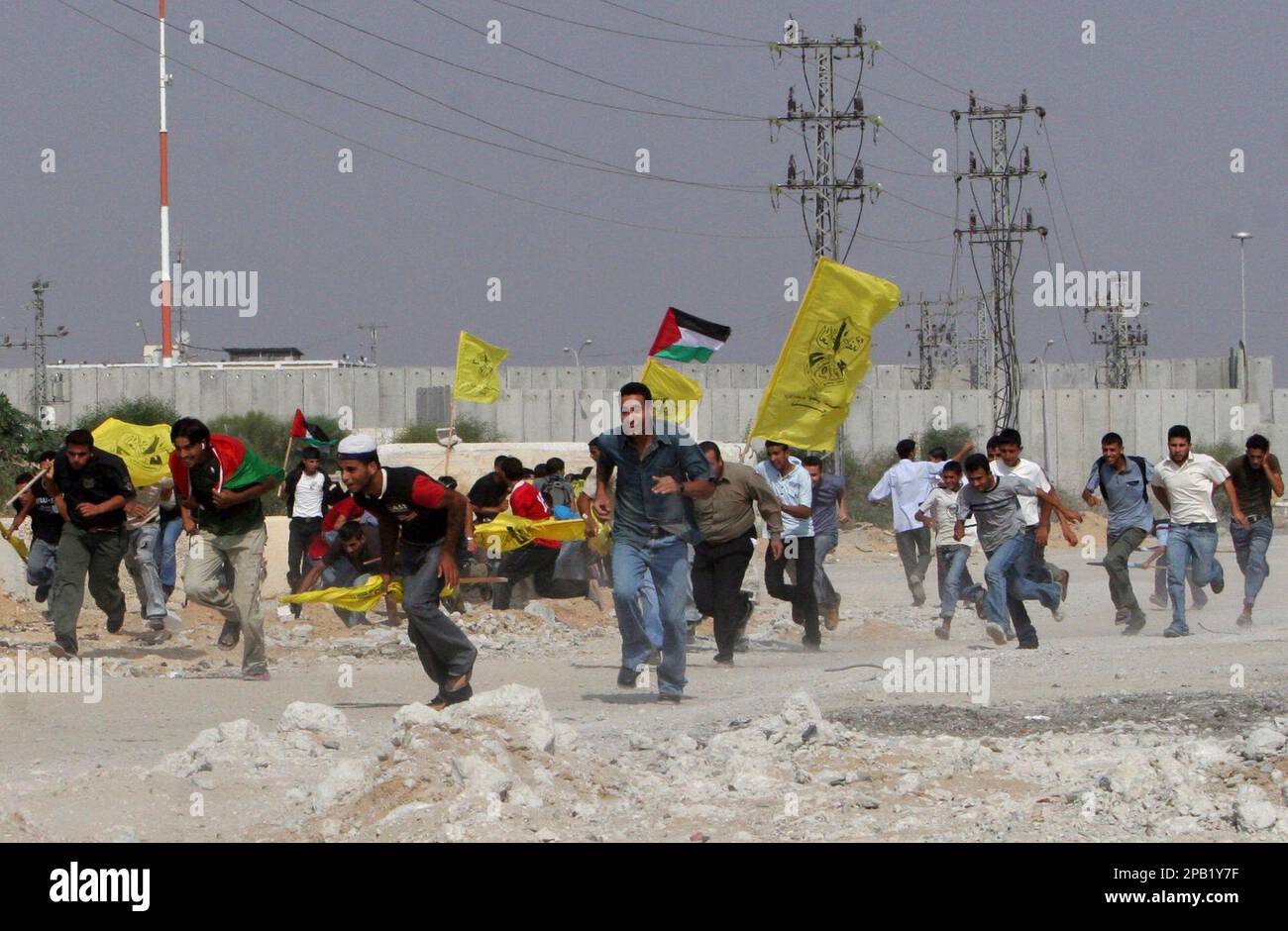 Palestinians carrying yellow Fatah flags run after Israeli troops ...