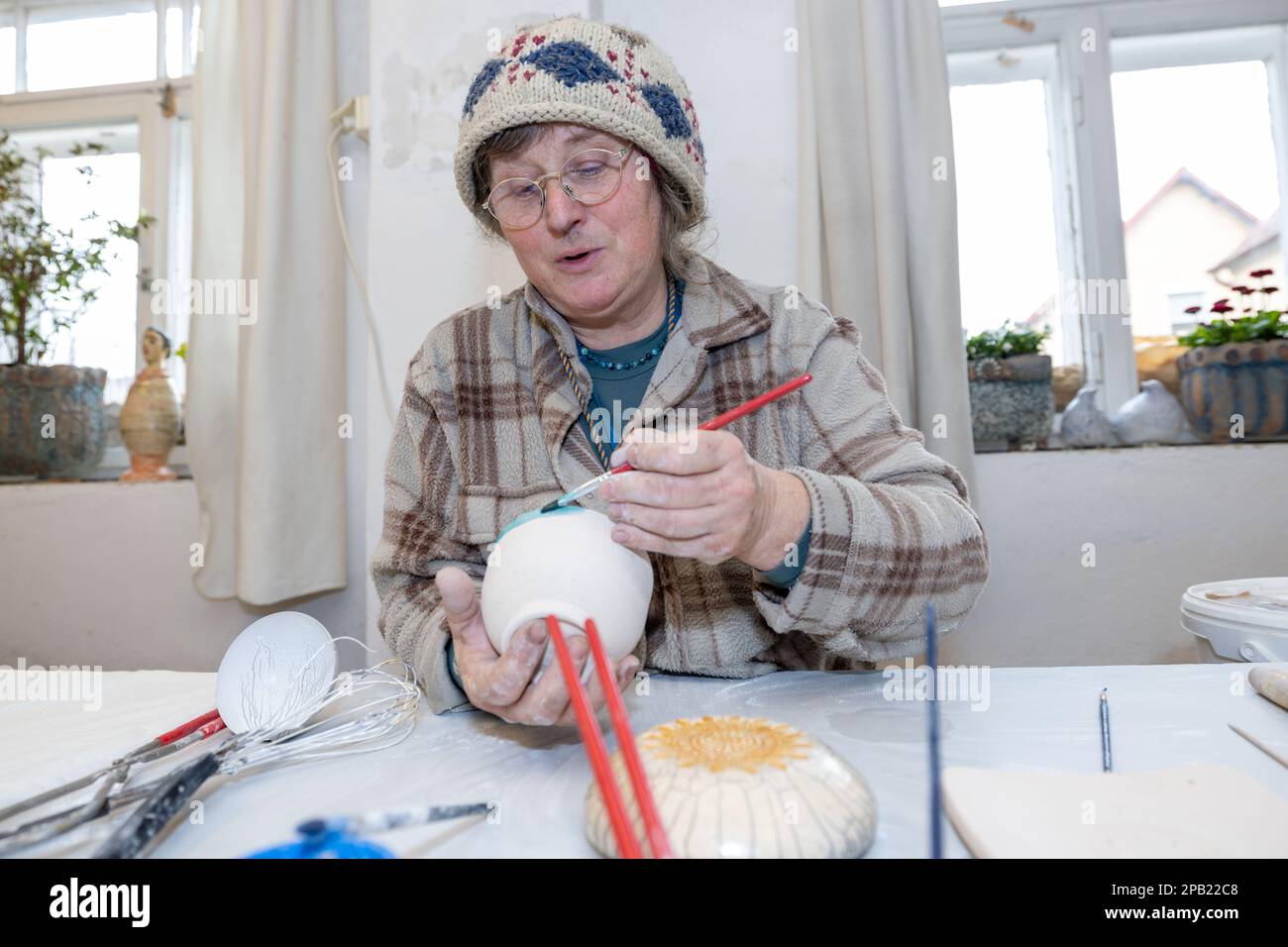 12 March 2023, Saxony, Börln: Heinke Binder paints a bowl made in the ...