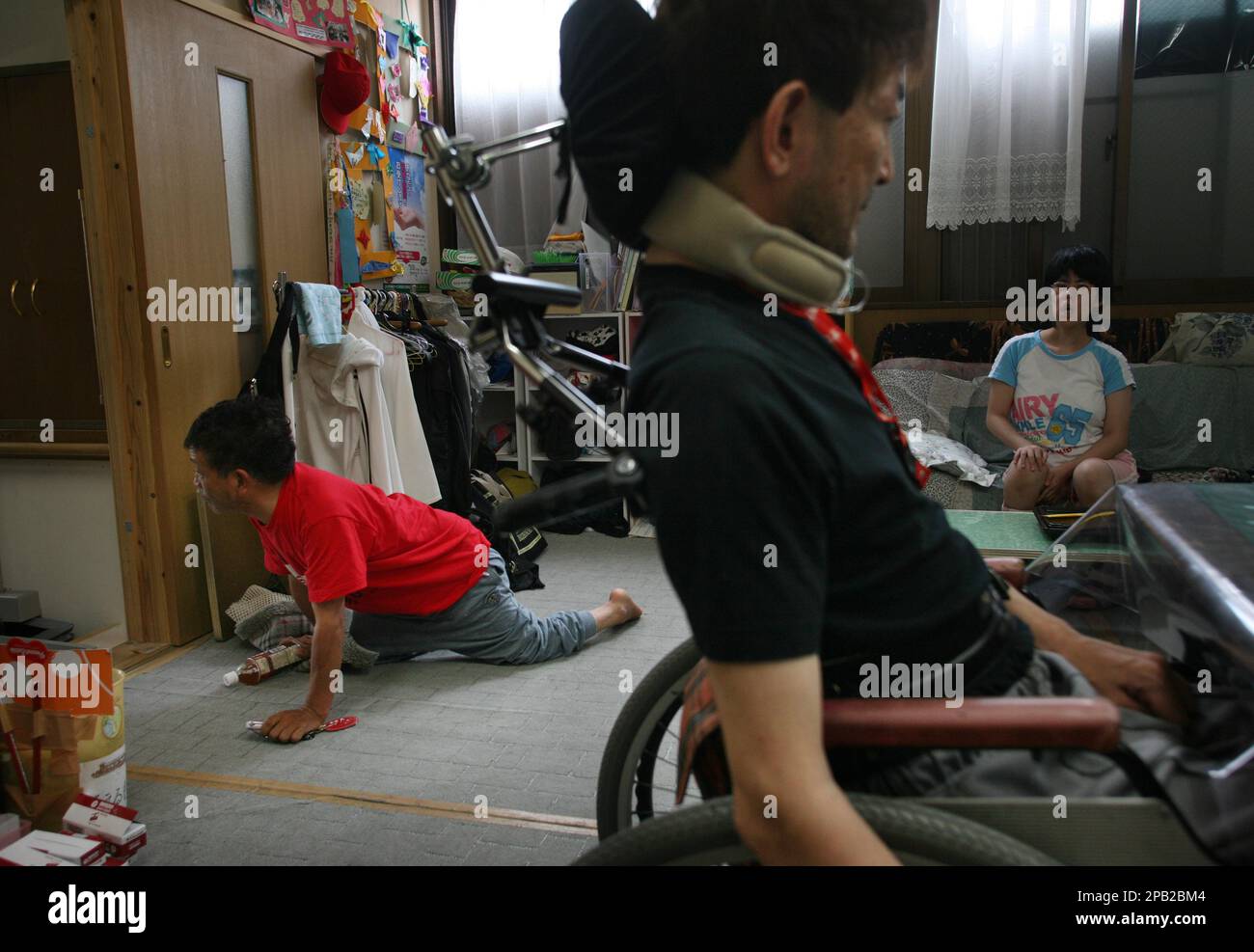 Unable to walk, Isamu Nagai crawls on the floor next to Youji Kaneko ...