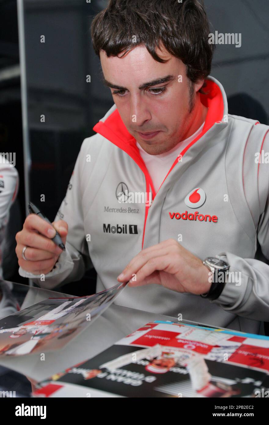 Spanish McLaren-Mercedes driver Fernando Alonso signs an autograph for ...