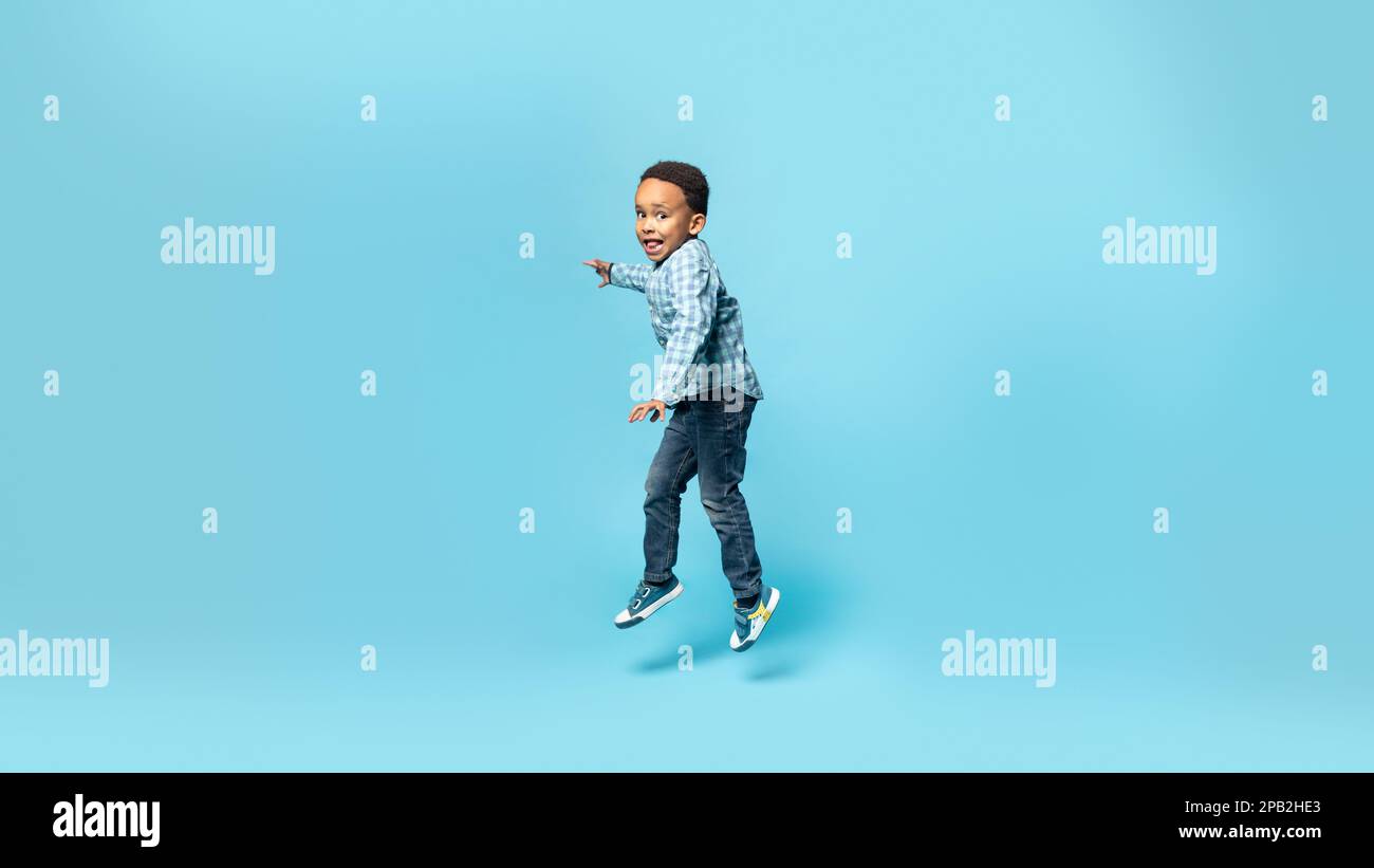 Funny african american little boy jumping in air, fooling around over ...