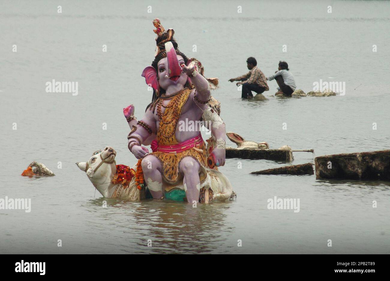 Two men are seen fishing as idols of Hindu God Ganesh lie partially ...