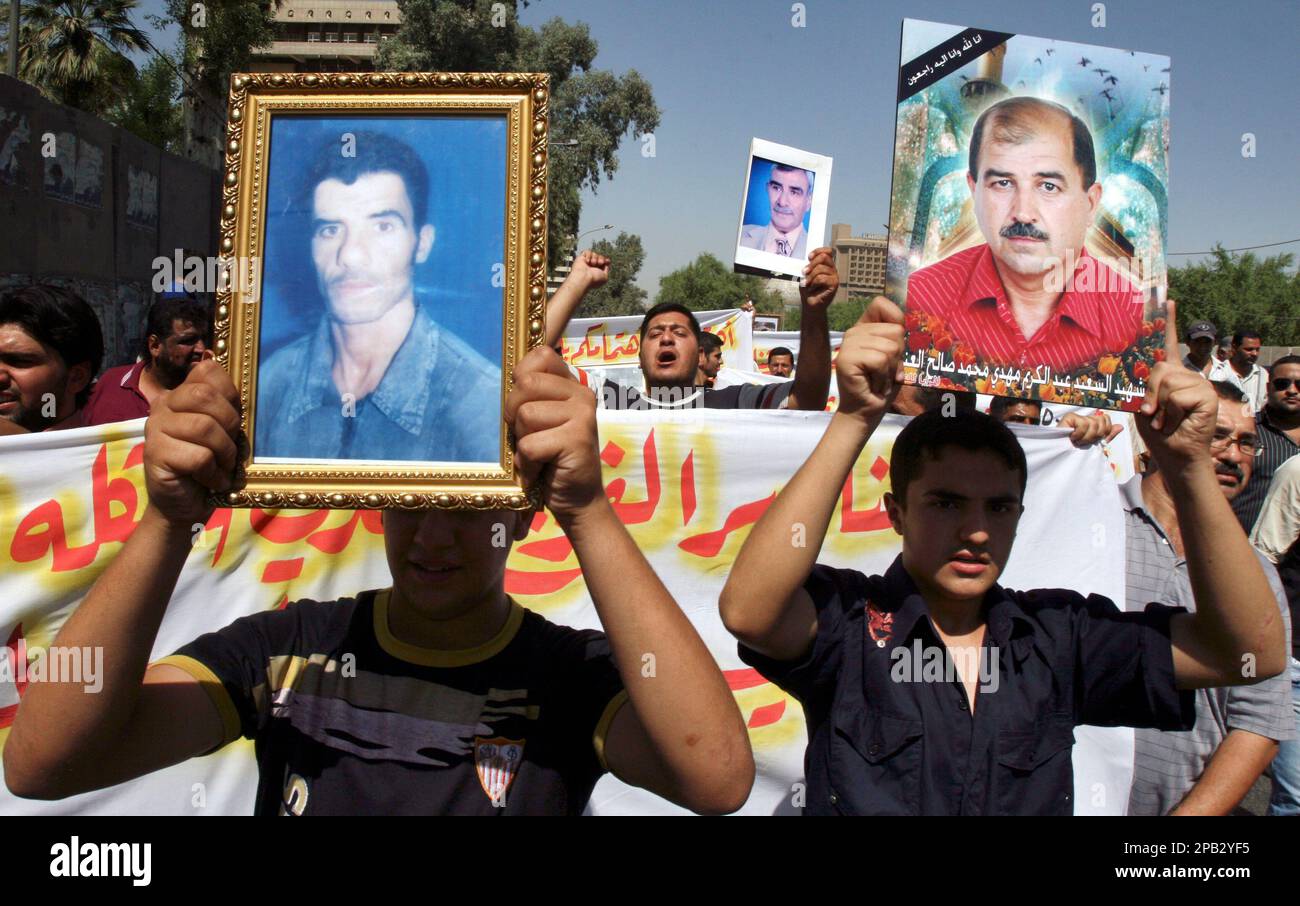 Men hold photos of their dead relatives as nearly 300 Shiite residents ...