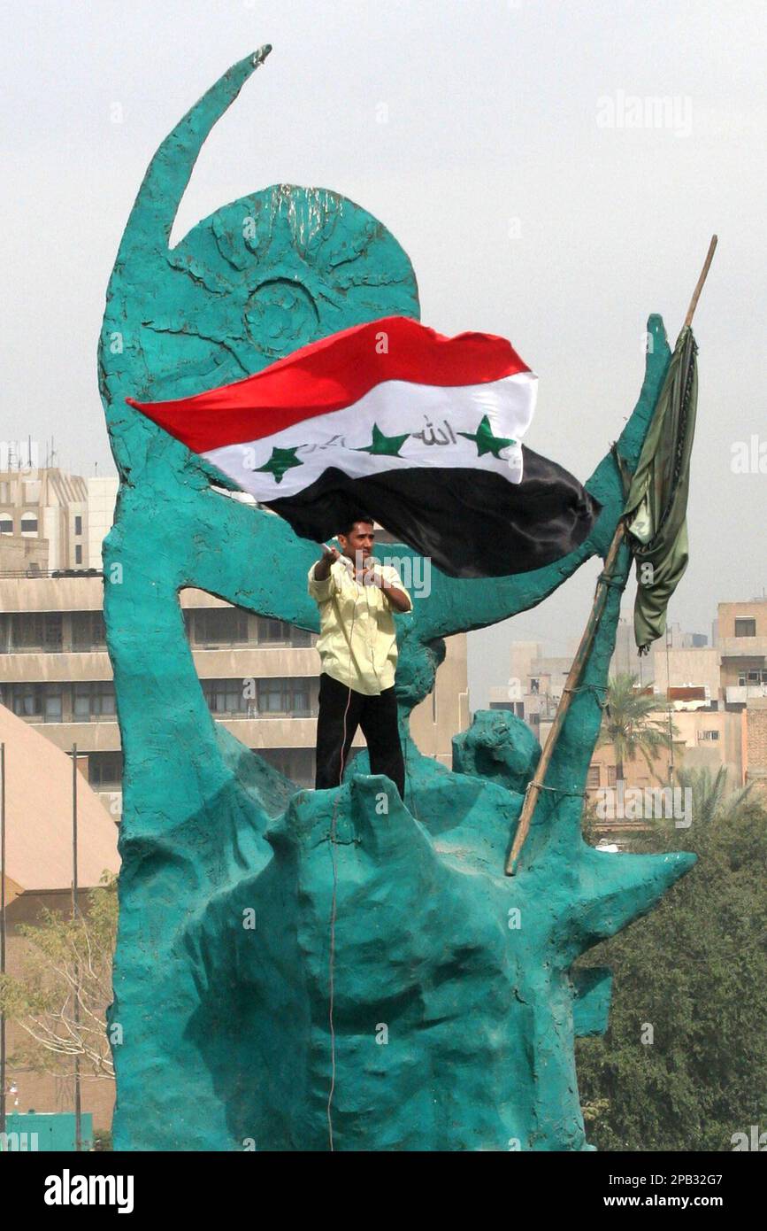 ** FILE ** An Iraqi man waves the nation's flag from atop a new ...