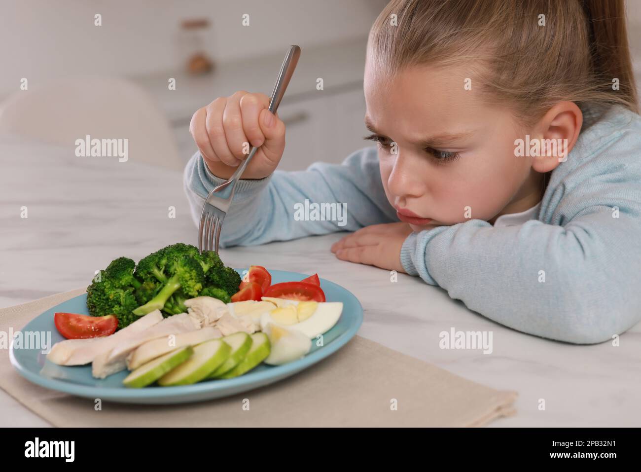 Cute little girl refusing to eat dinner in kitchen Stock Photo - Alamy