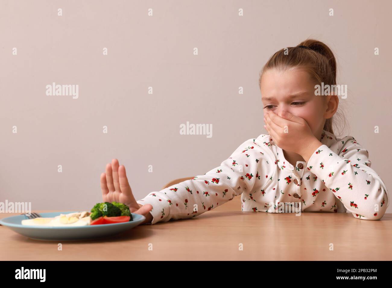 Cute little girl covering mouth and refusing to eat her dinner at table ...