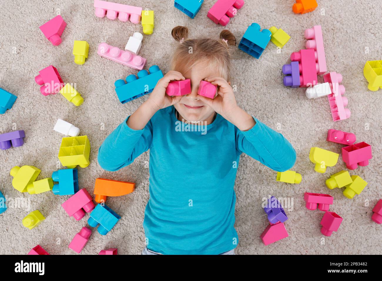 Cute little girl playing with colorful building blocks on floor, top ...